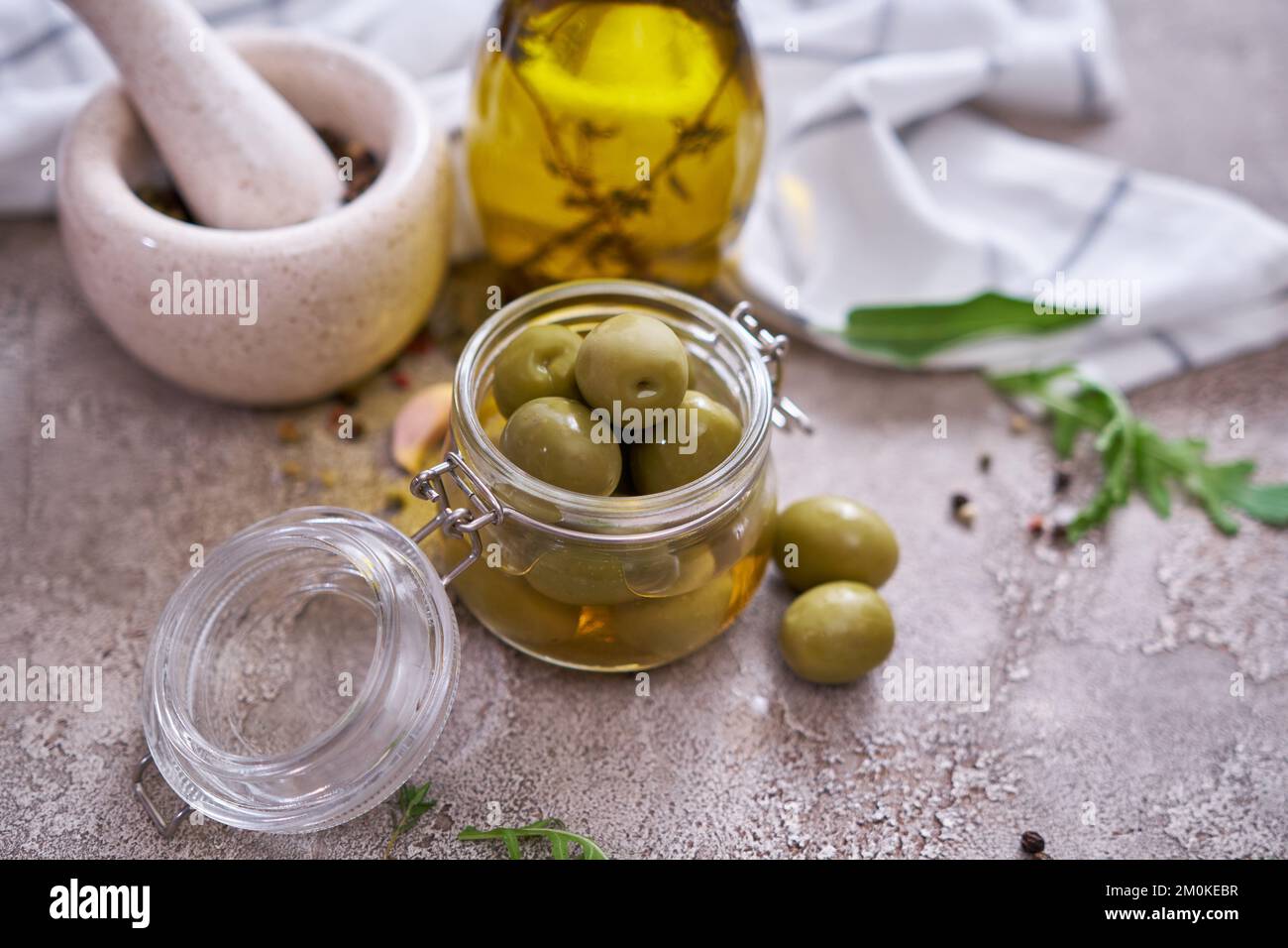 Canned green olives in a glass can and small bottle of olive oil with ...