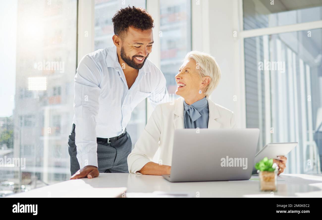 Two happy diverse colleagues working together on a laptop and digital ...