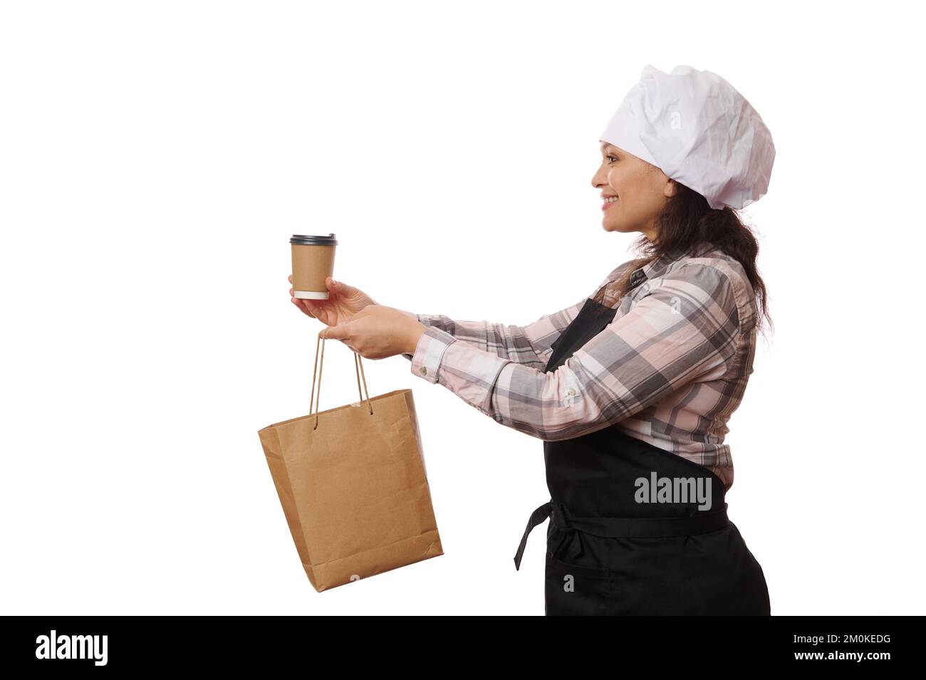 Side portrait nice waitress in apron and chef hat, smiles holding out ...
