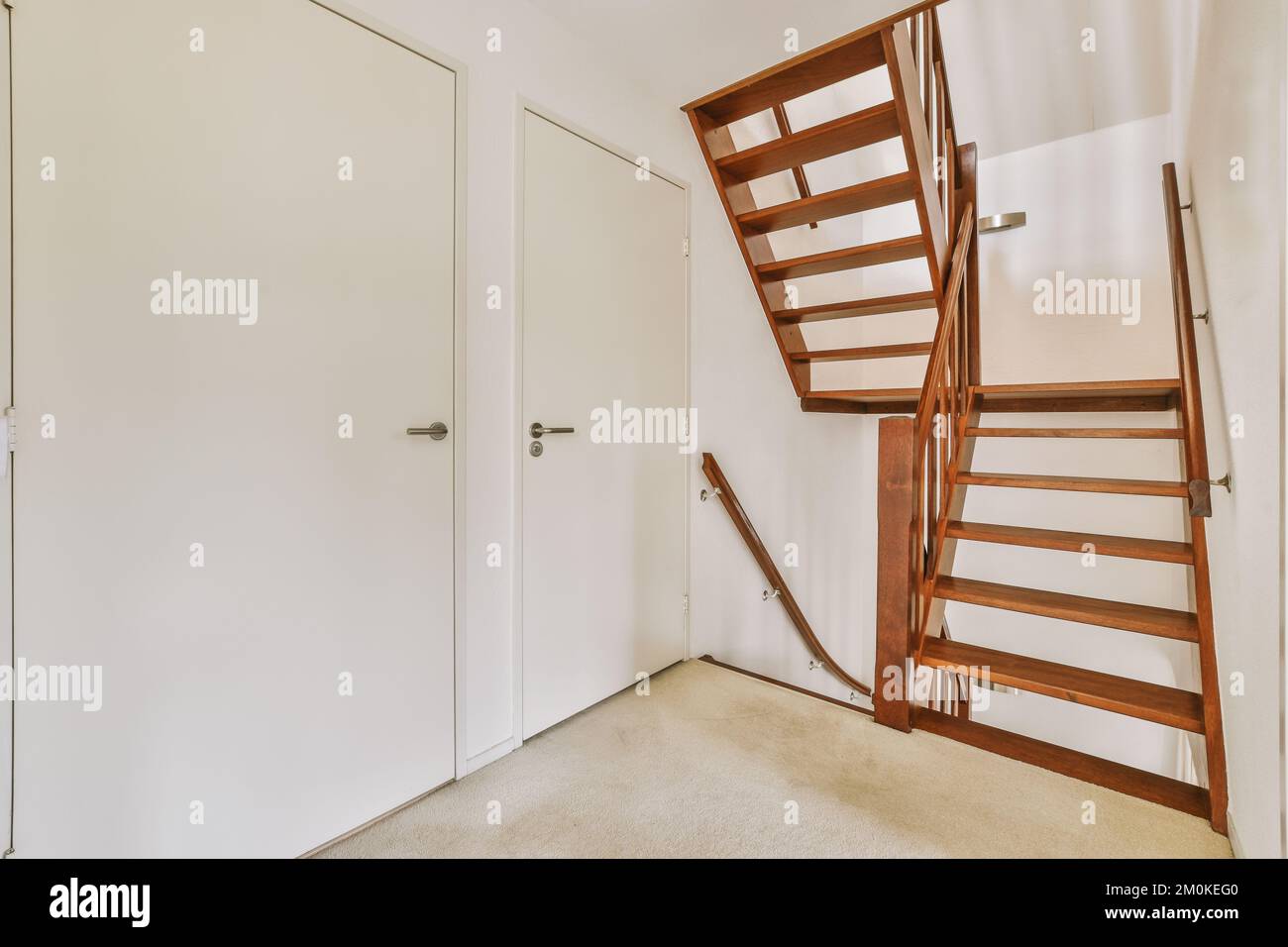 White hallway with wooden stairway leading to second floor of modern ...