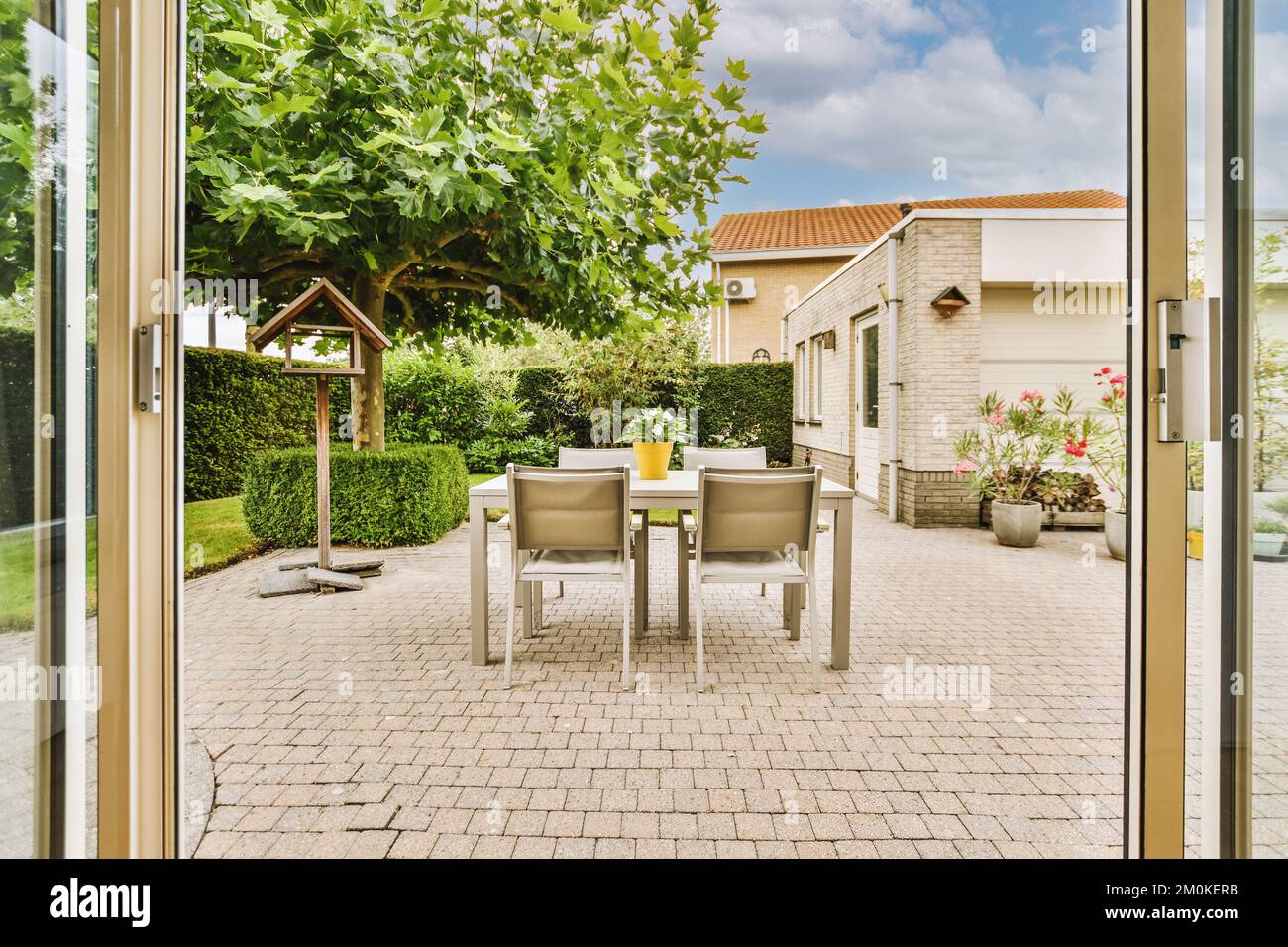 Neat paved patio with sitting area and small garden near wooden fence ...