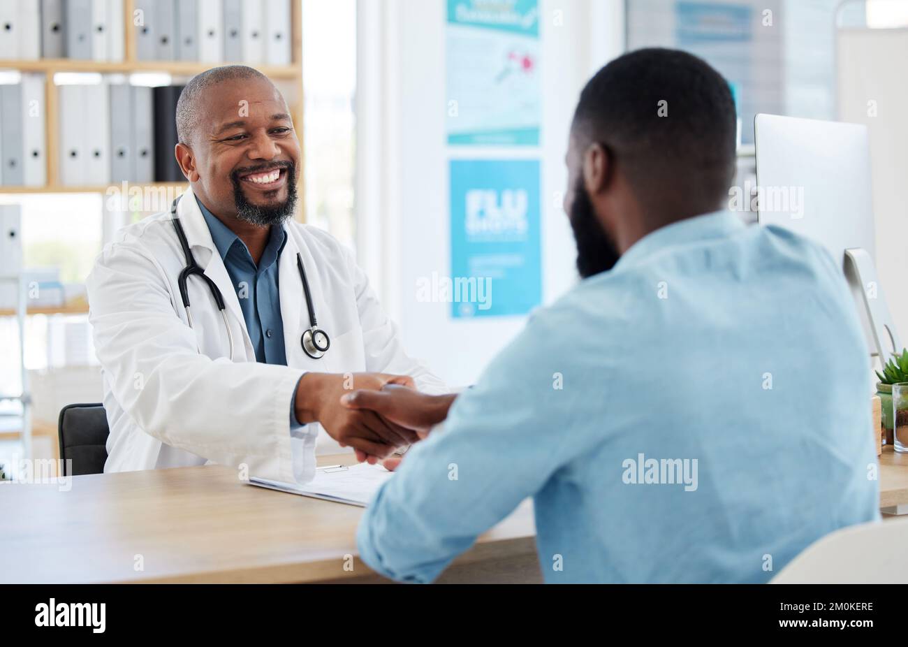 Happy doctor greeting his patient with a handshake. Mature doctor ...