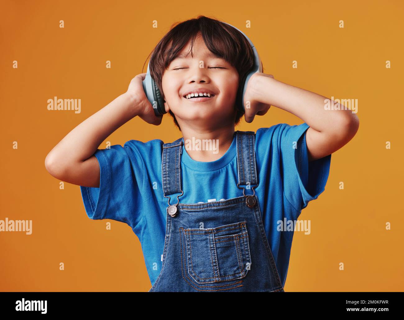 A cute little asian boy enjoying listening to music while wearing ...