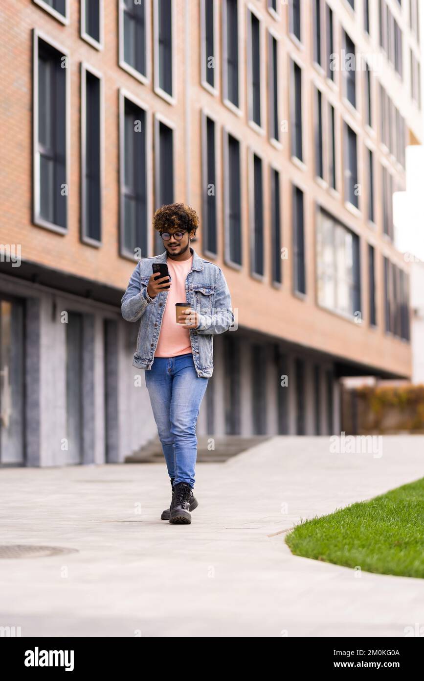 Indian man use phone drinking phone while walking on the street Stock ...