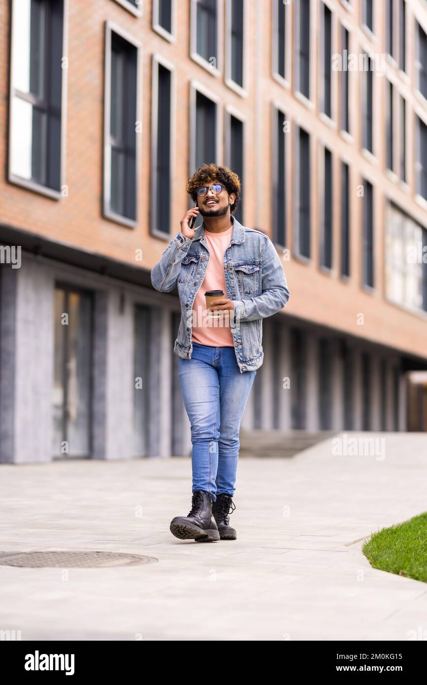 Indian man use phone drinking phone while walking on the street Stock ...