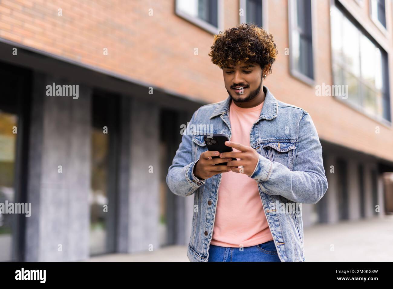 Indian male student texting on smartphone in the street Stock Photo - Alamy