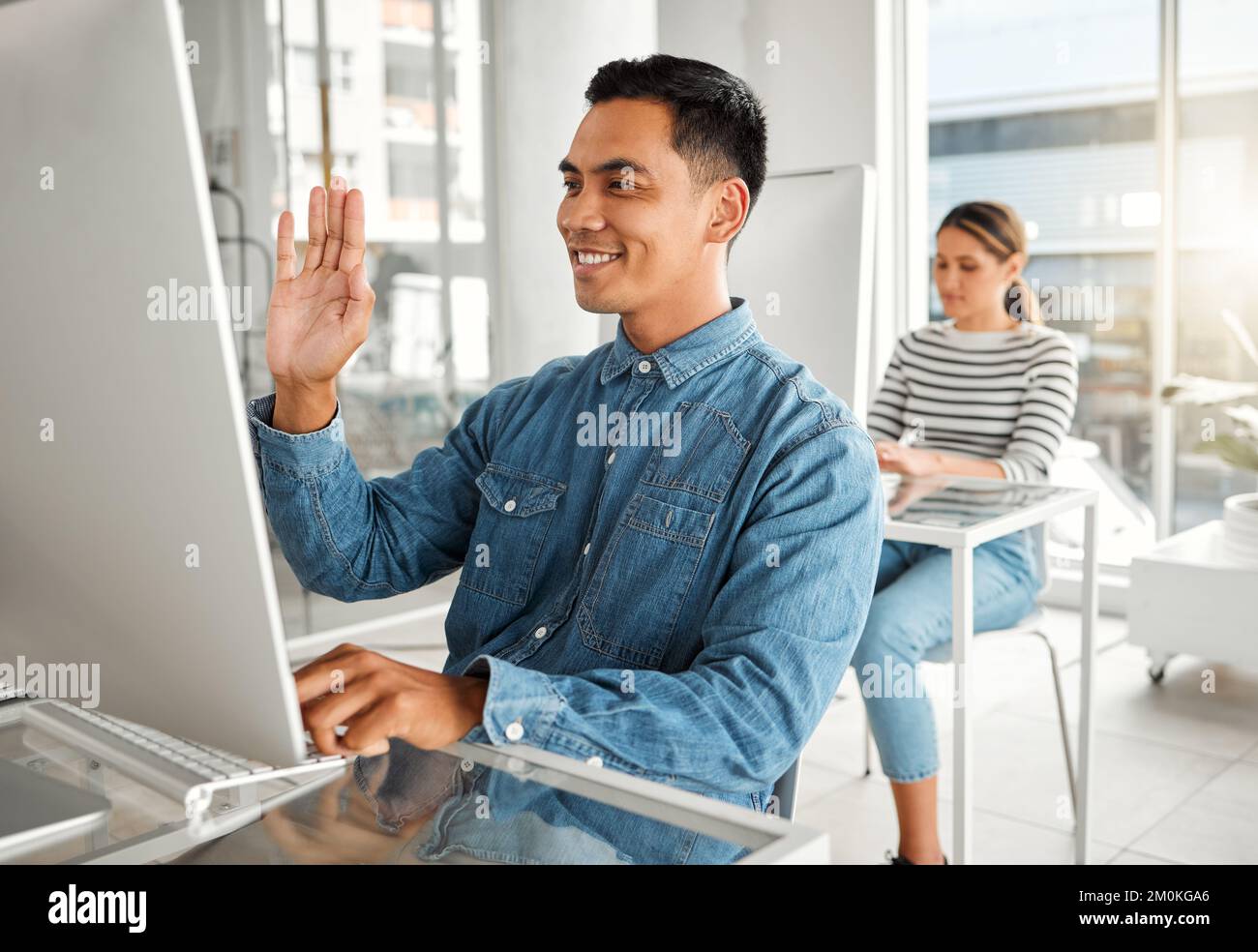 Young cheerful asian businessman waving while on a video call using a ...