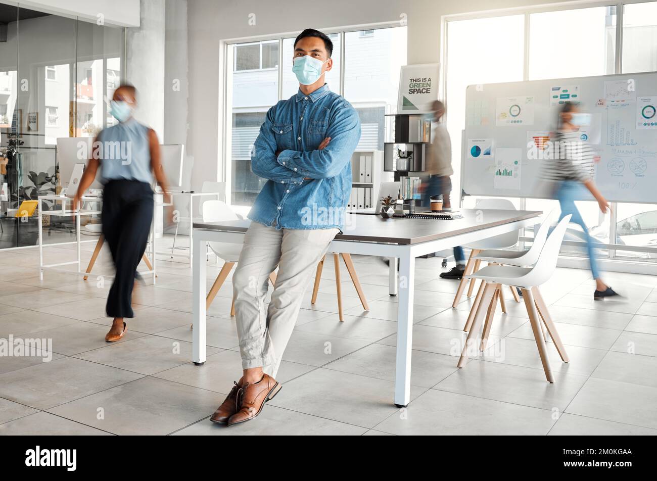 Young asian businessman standing with his arms crossed and wearing a ...