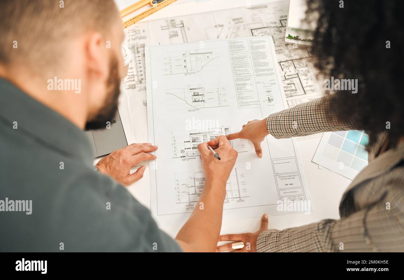 Architects working on a blueprint from above. Businesspeople writing on ...