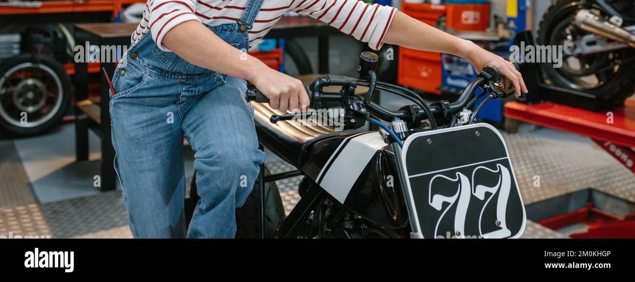 Mechanic woman starting custom motorcycle on factory Stock Photo - Alamy