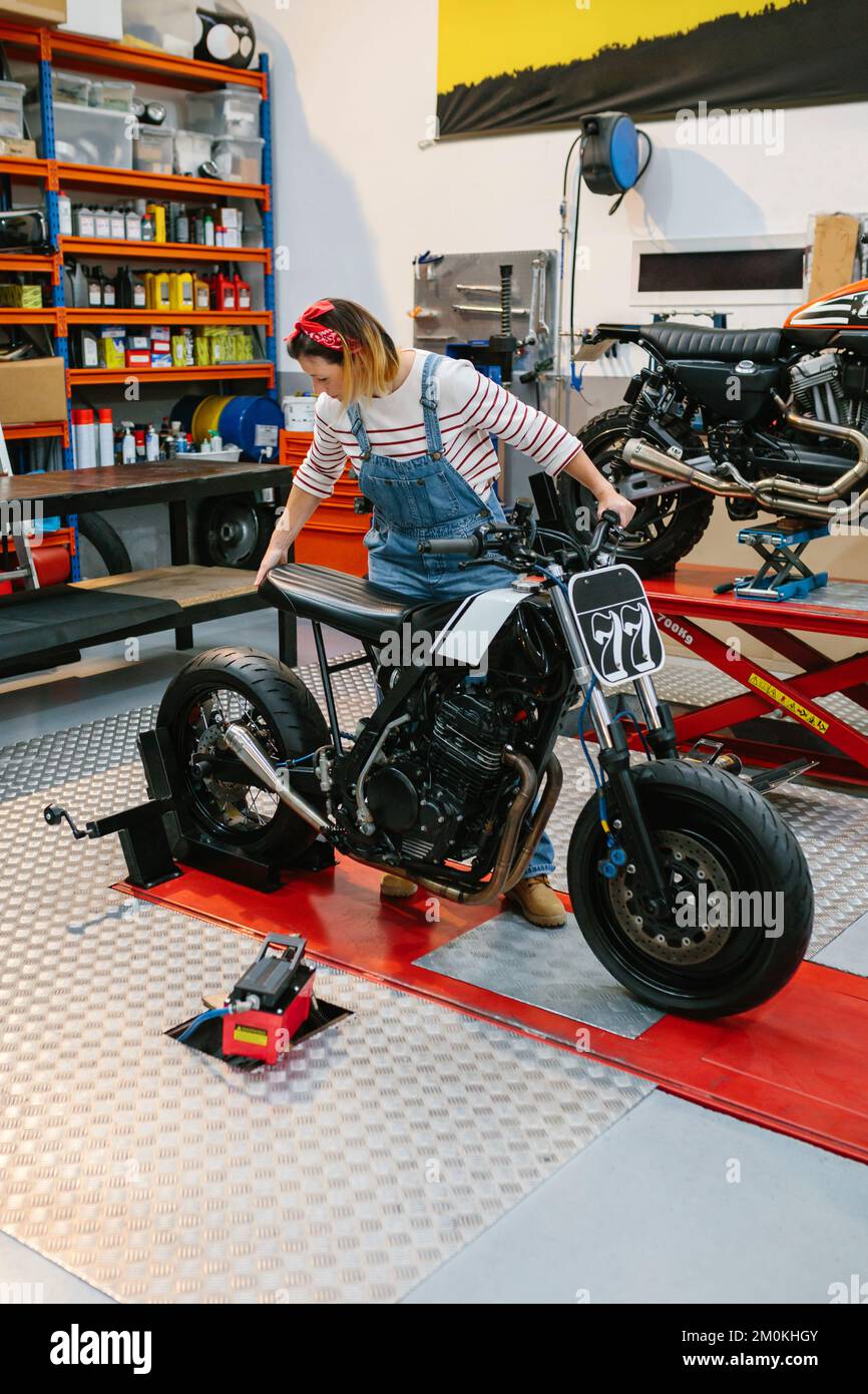 Mechanic woman placing custom motorcycle over platform Stock Photo - Alamy