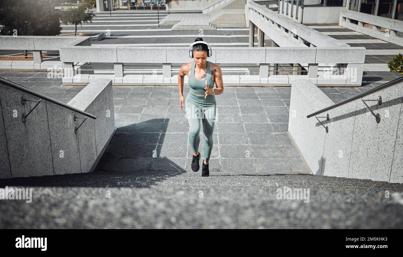 Young mixed race female athlete wearing gymwear and headphones while ...