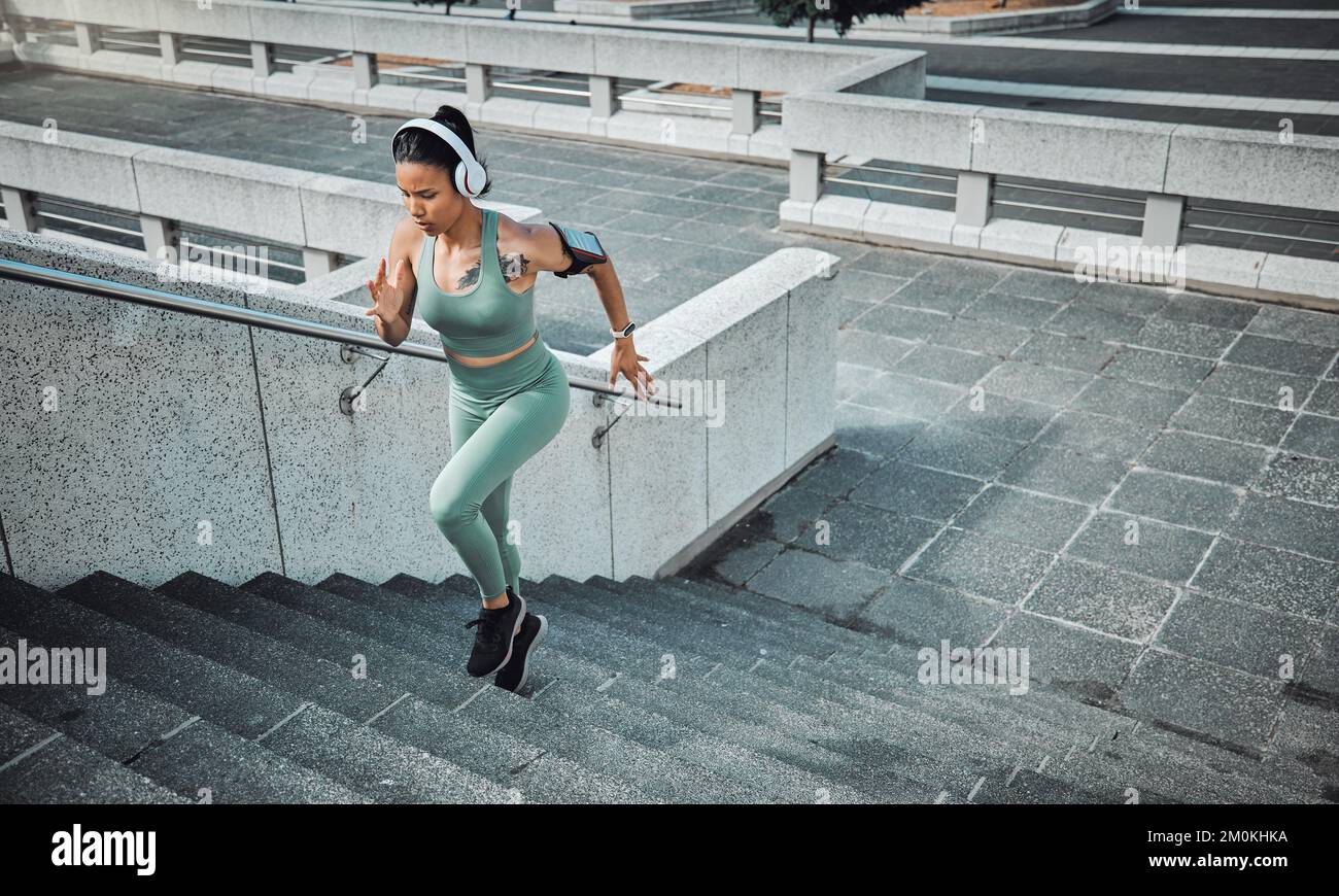 Young mixed race female athlete wearing gymwear and headphones while ...