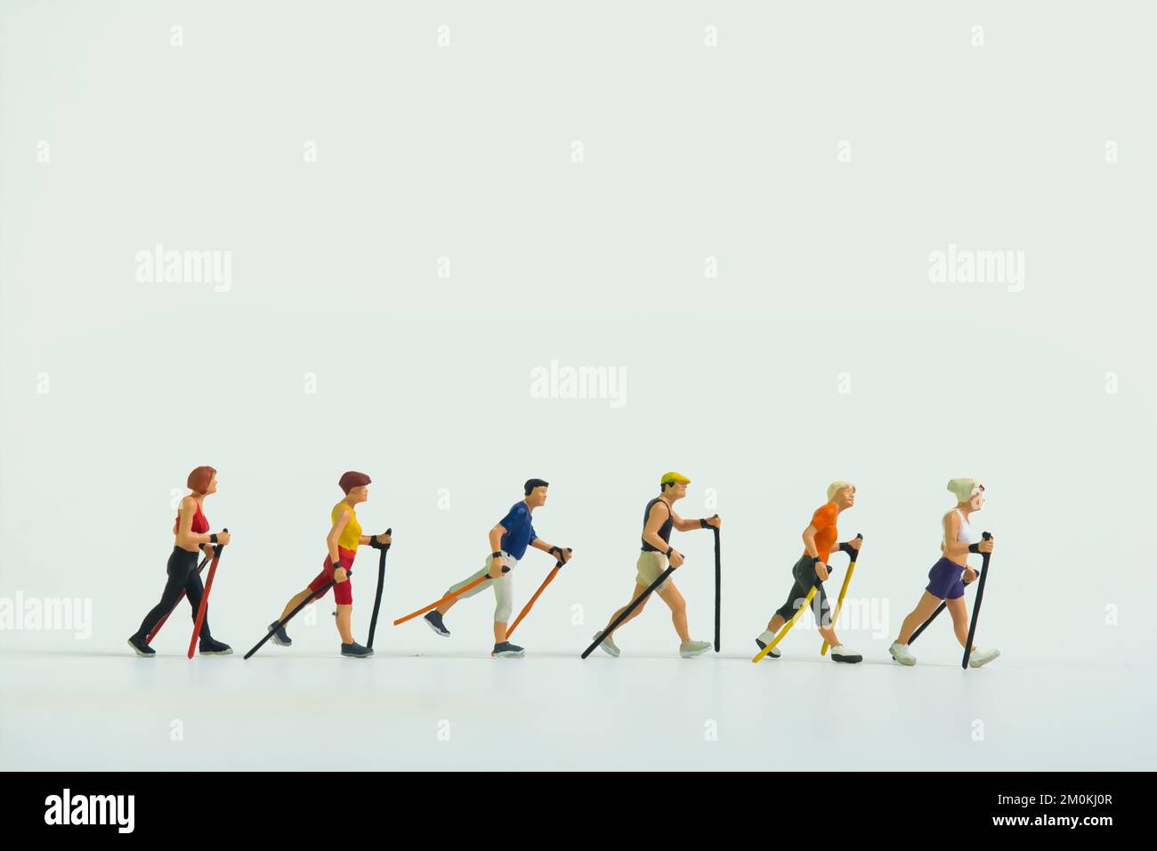 The miniature figures of hikers walking holding sticks in both hands on ...