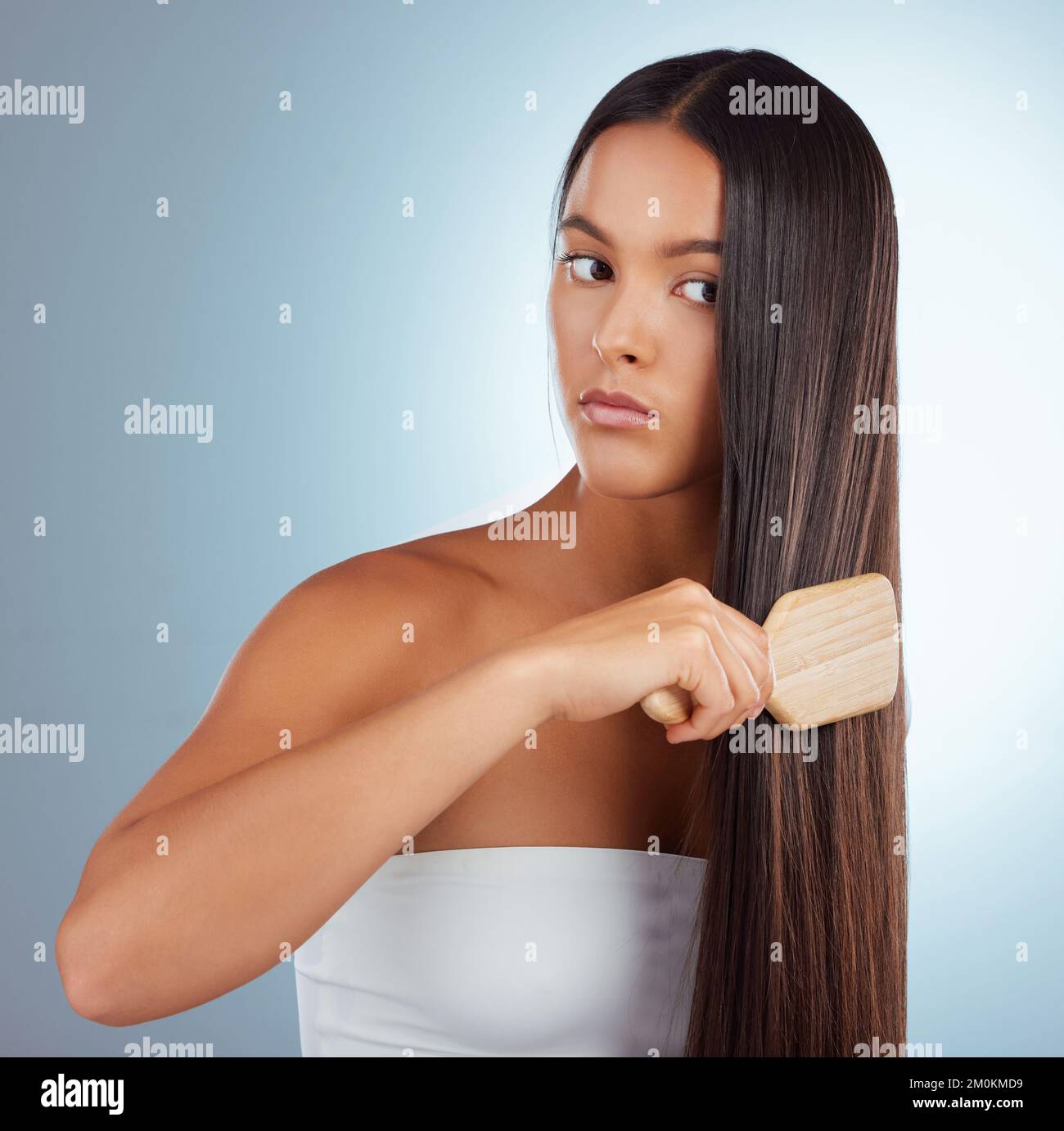 A beautiful young mixed race woman brushing her healthy strong hair ...