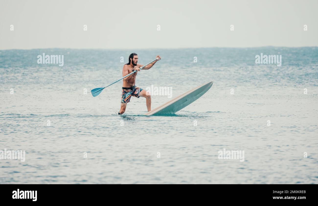 Sea man sup. Asian athlete man swimming in sea and paddleboarding at ...
