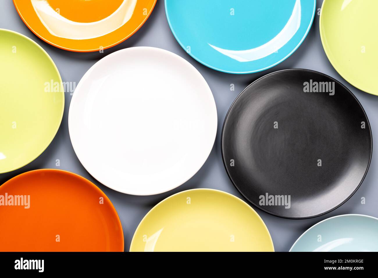 Different clean colorful plates on grey background. Flat lay with copy ...