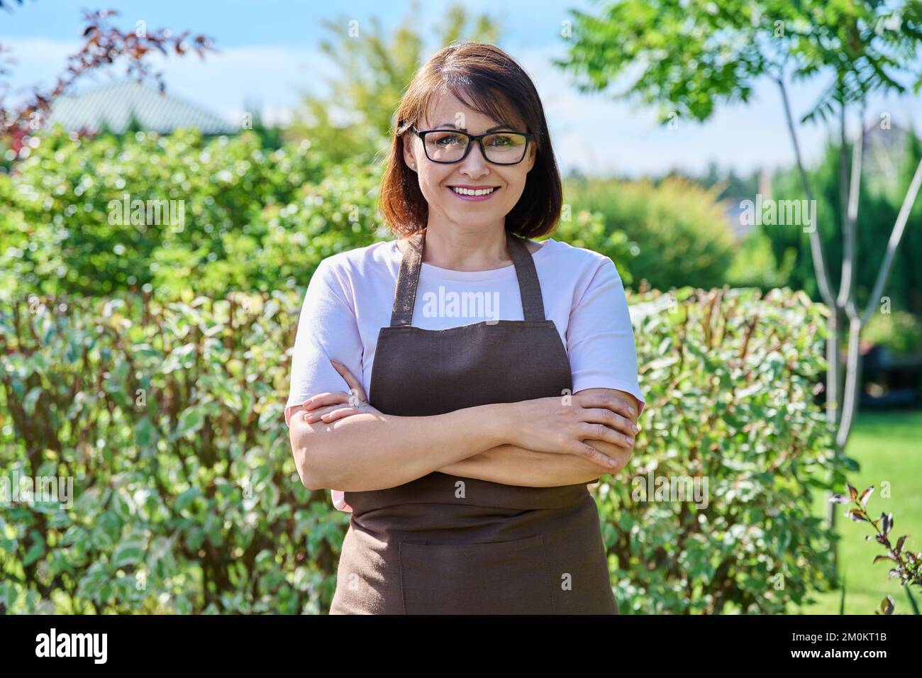 Outdoor portrait smiling female gardener looking at camera in backyard ...