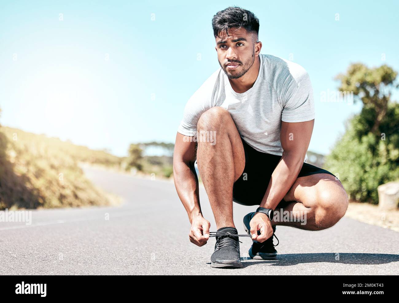 Athletic young mixed race man tying his shoelaces before a run ...