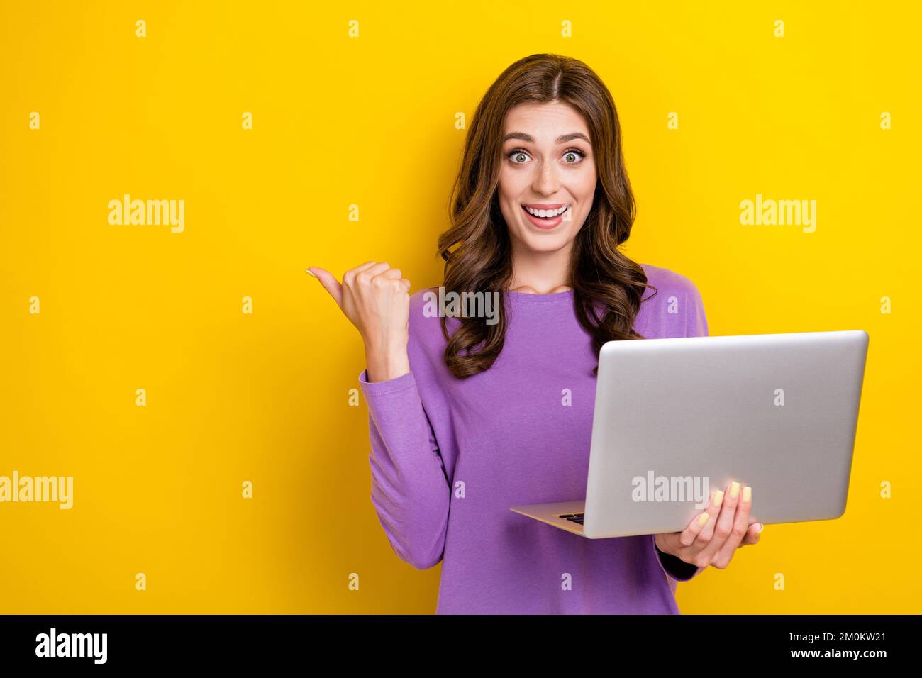 Portrait of excited cheerful girl hold netbook indicate thumb finger ...
