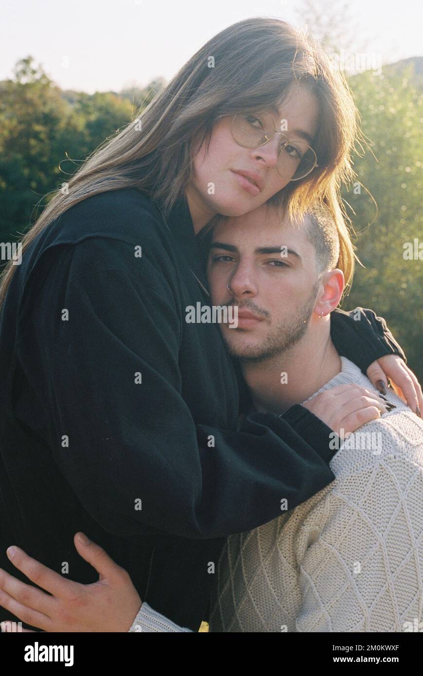 A vertical of a couple hugging each other and looking at the camera ...