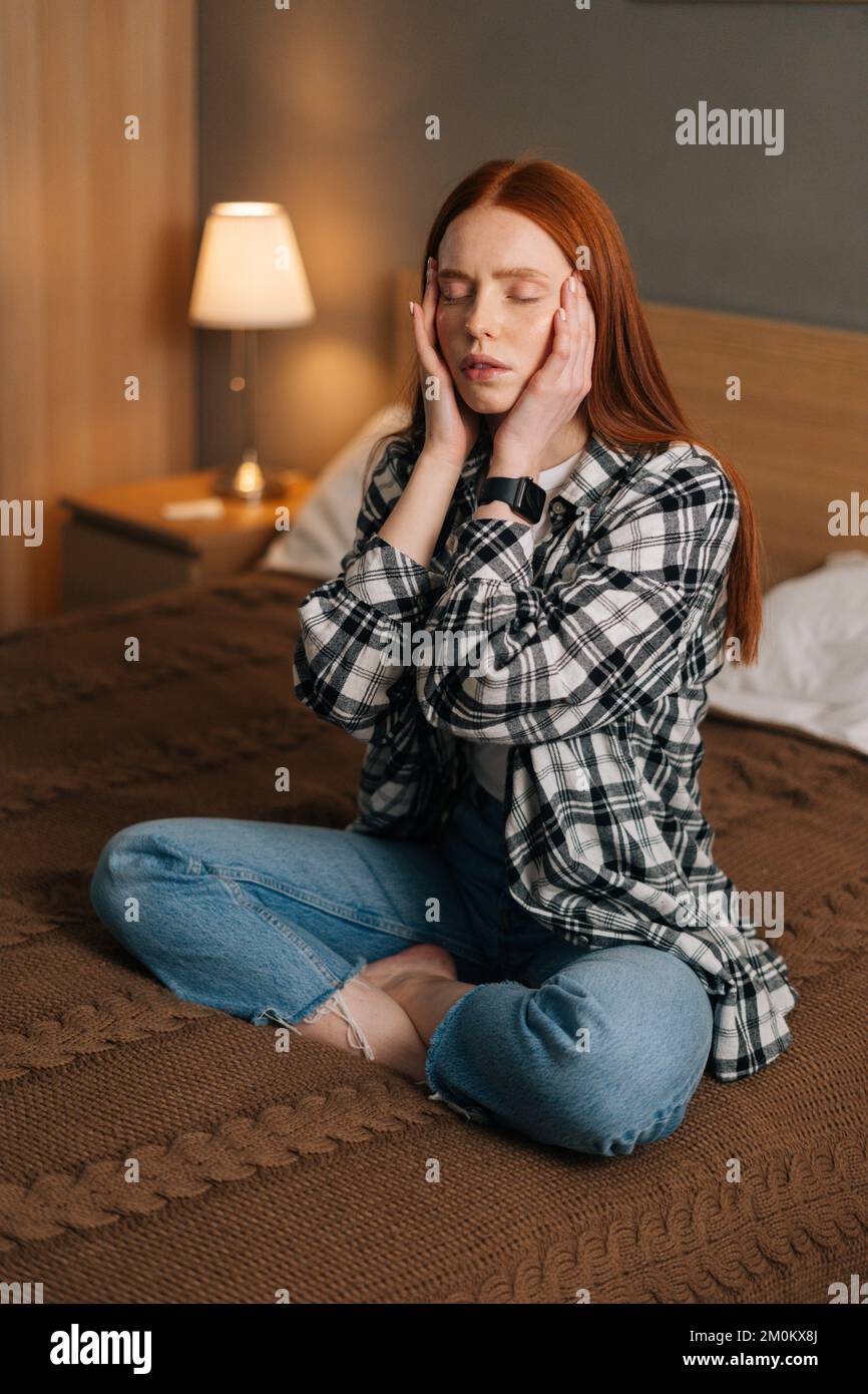 Vertical portrait of sad sick young woman with closed eyes touch head ...