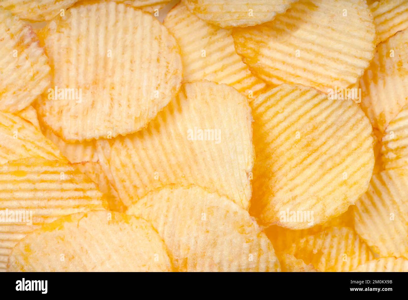 Yellow crispy ridged potato chips close up. Food background, banner ...