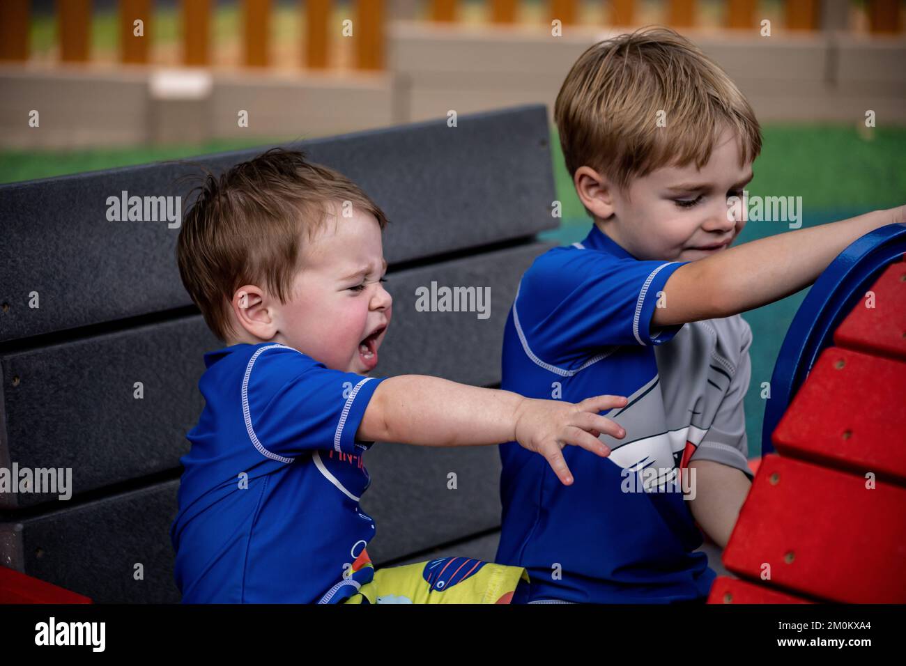 A closeup of two brothers playing at the playground younger reaching ...