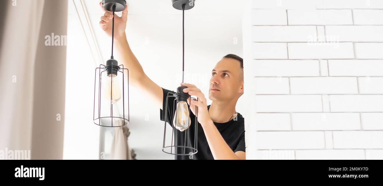 Worker repairing lamp on stretch ceiling indoors Stock Photo - Alamy