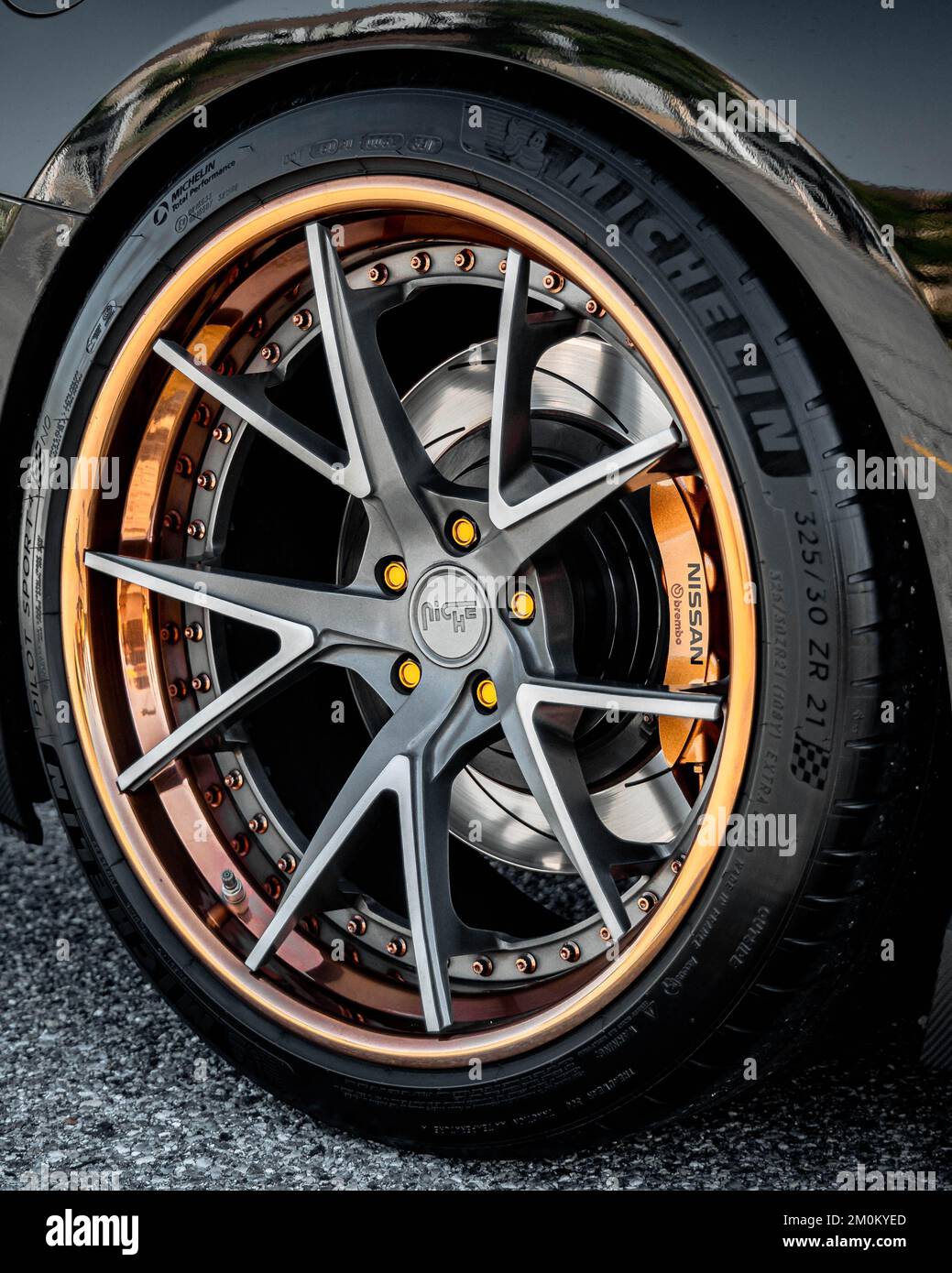 A vertical shot of a multi piece of gold and silver Wheel on a Nissan ...