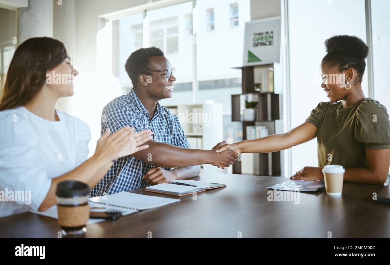 Young happy businesspeople shaking hands in a meeting with a colleague ...