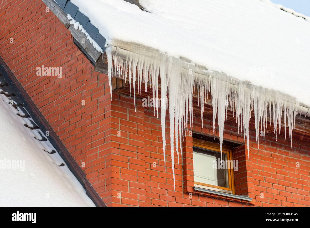 Huge sharp icicles of ice hang from the roof of a residential building ...