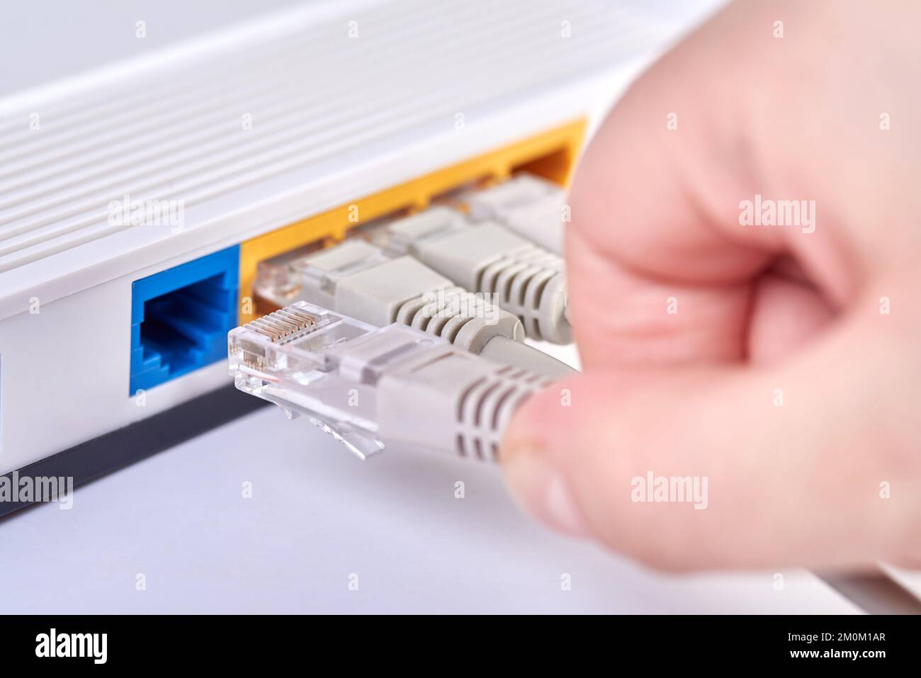 The hand inserts the Internet cable into the router Stock Photo - Alamy