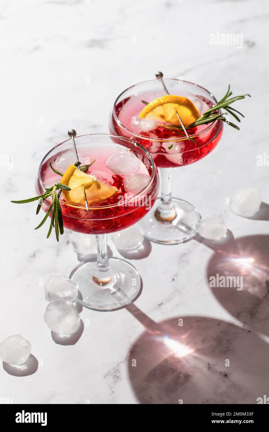 Two wineglass of Pomegranate Christmas iced cocktail with rosemary and ...