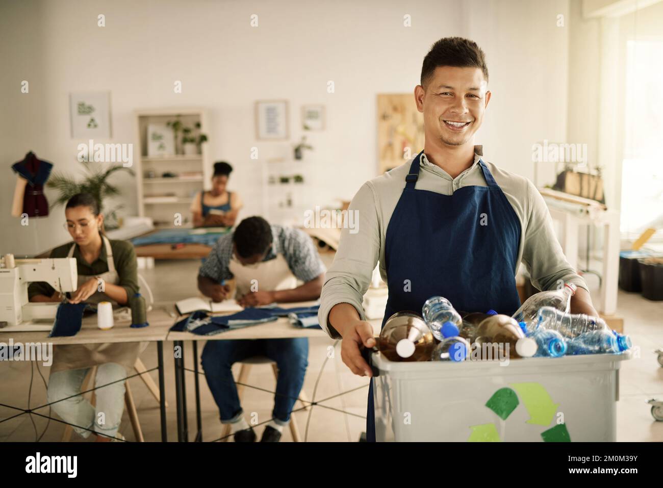 Portrait of designer holding recycled plastic bottles in a bucket ...