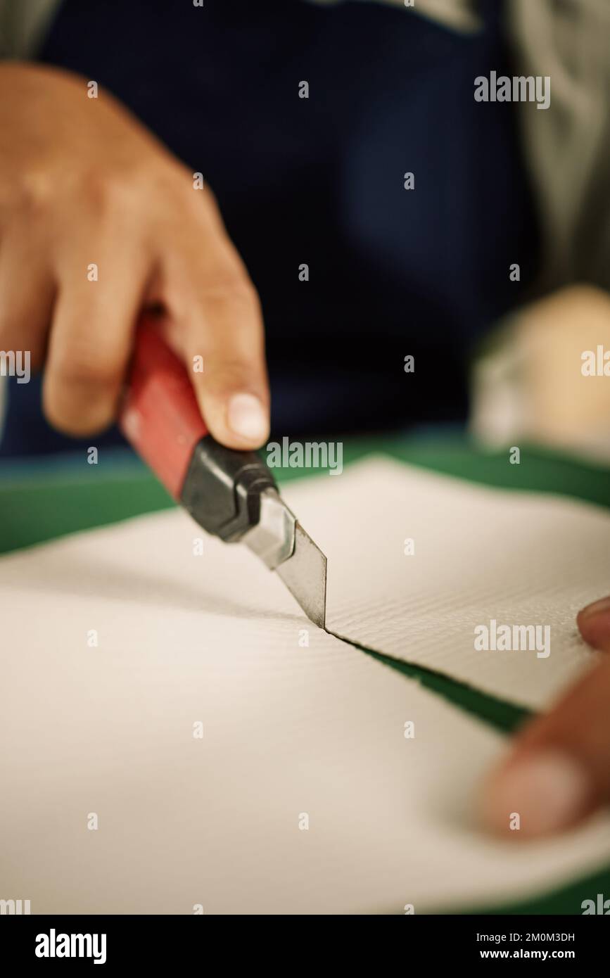 Closeup of hands of designer cutting paper with a knife. Zoom into ...