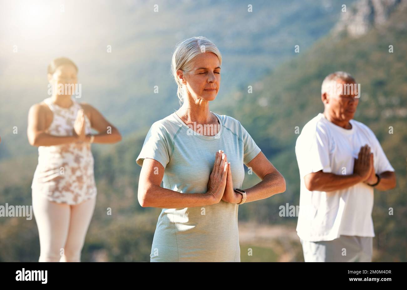 Three senior people meditating with joined hands and closed eyes ...