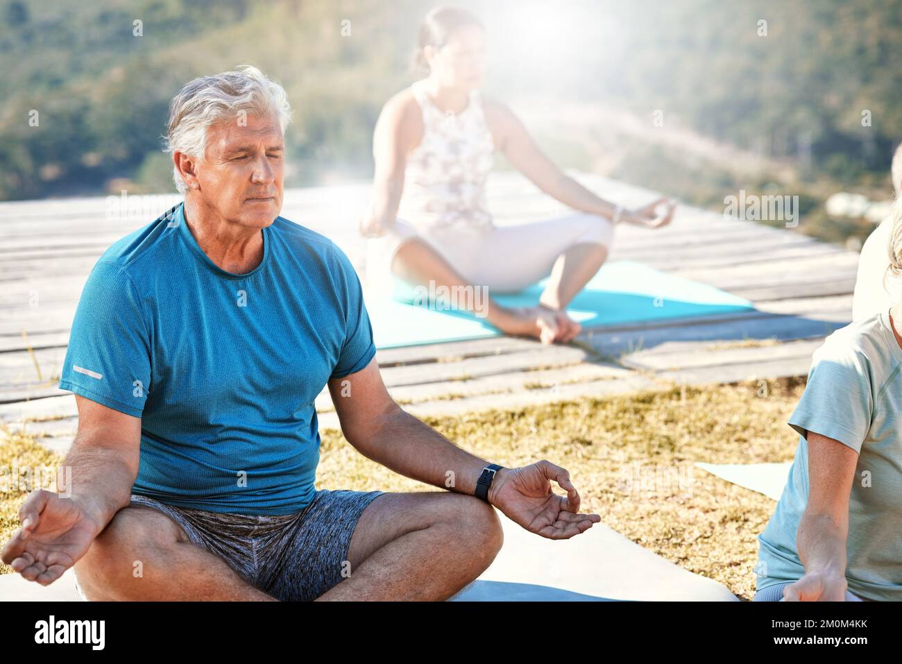 Senior men and women sitting in lotus position and practising ...
