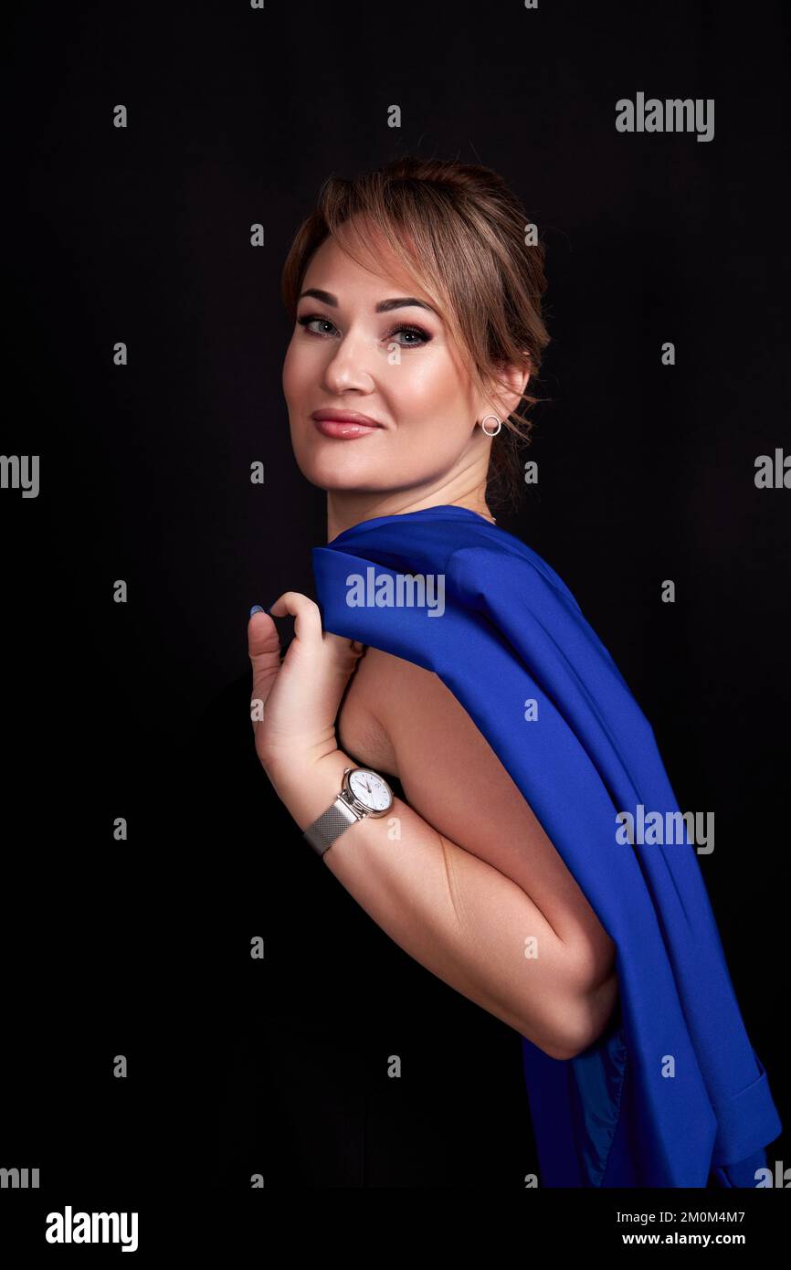 caucasian adult woman threw a blue jacket over her shoulders on a black ...