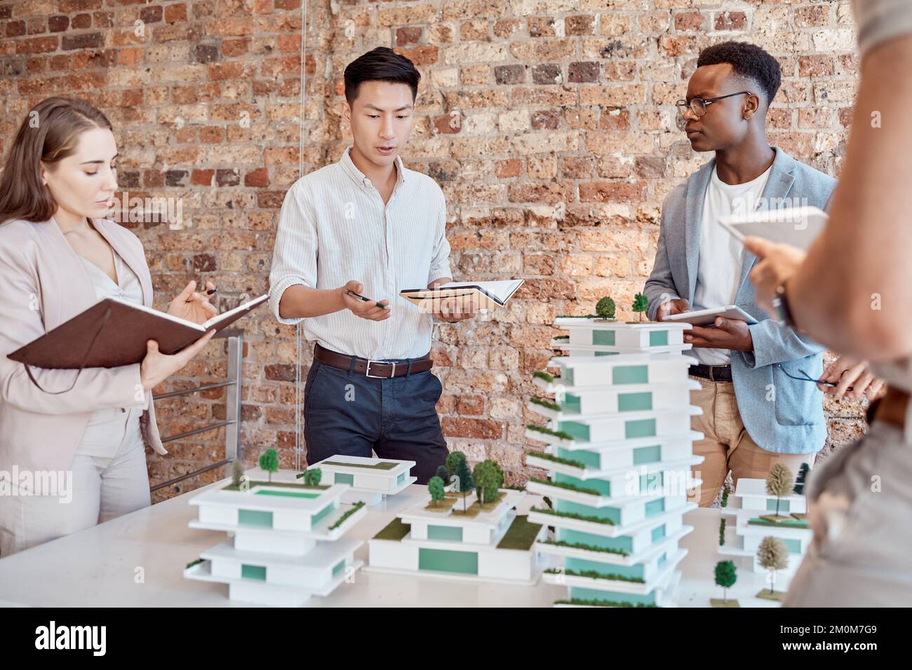 Group of diverse architects discussing plans, blueprints and schematics ...