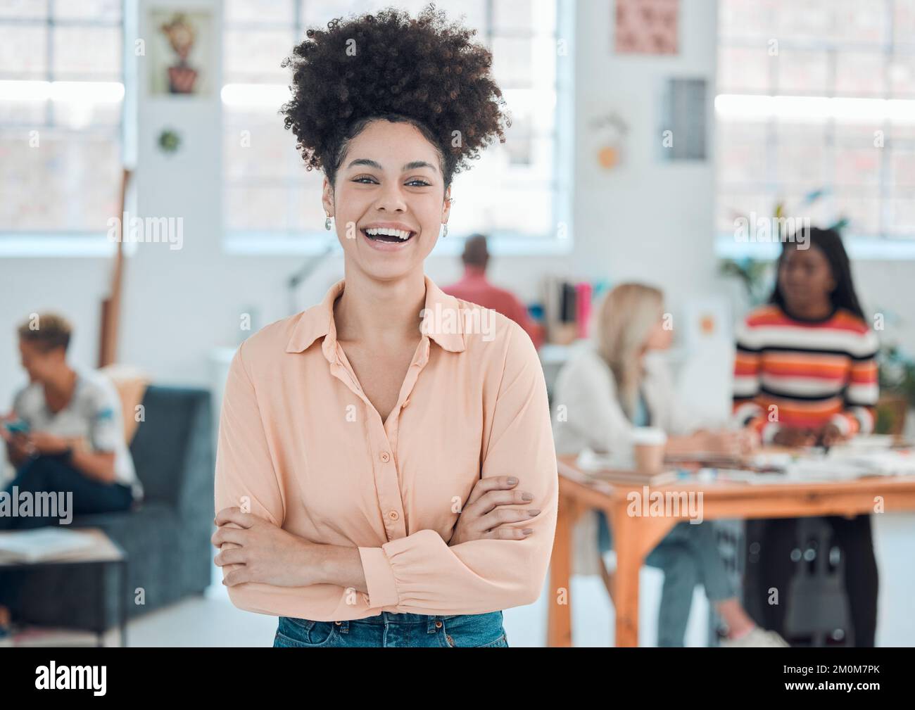 Young cheerful mixed race businesswoman standing with her arms crossed ...