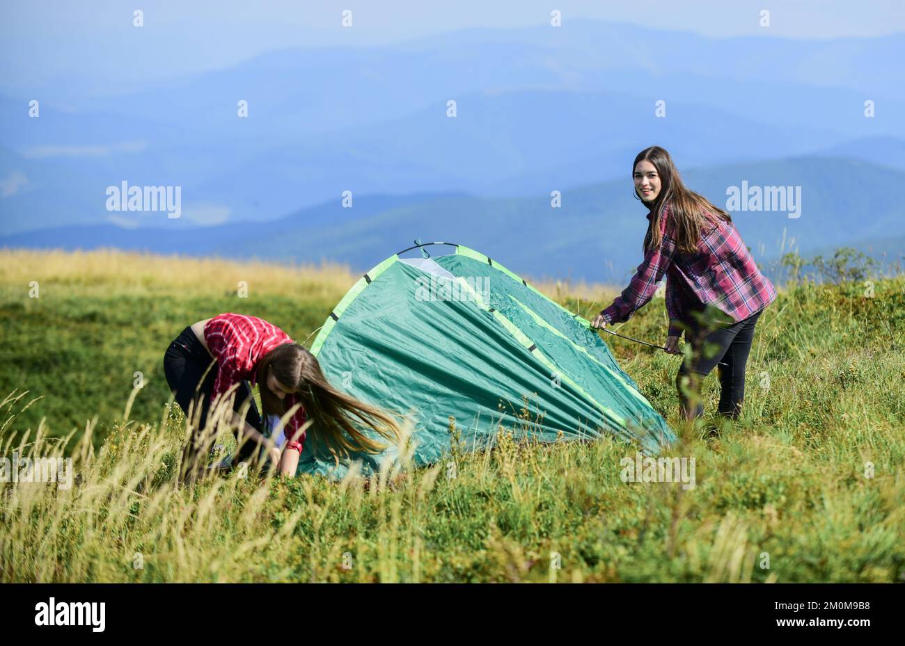 Girls set up tent on top mountain. Temporary housing. Vacation in ...