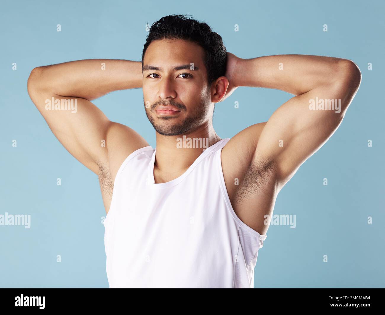 Handsome young hispanic man posing in studio isolated against a blue ...