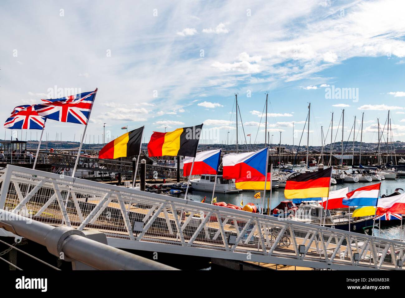 Flags of many countries fly along the walkway between Torquay Harbour ...