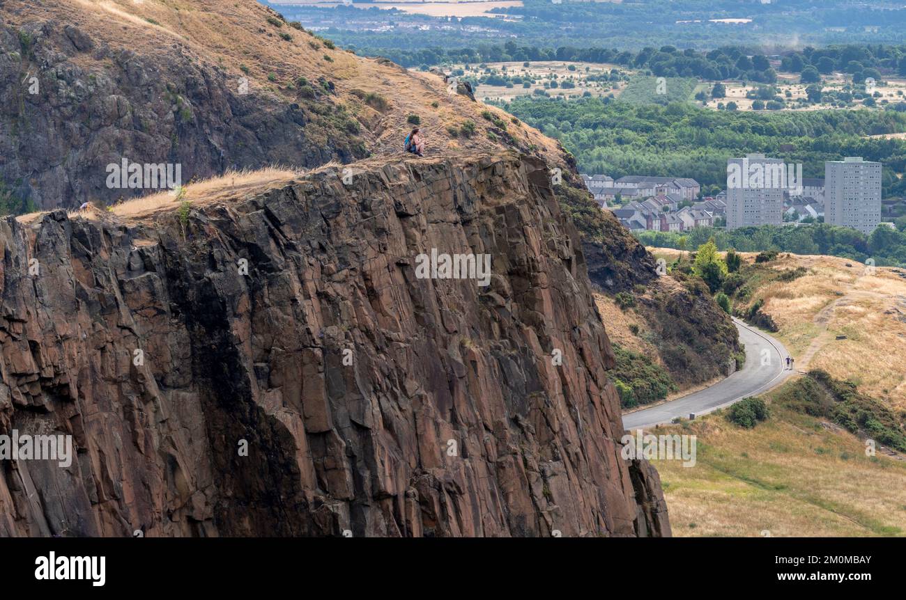 Visitors climbing to Arthur's seat,stand at the precipice of a high ...