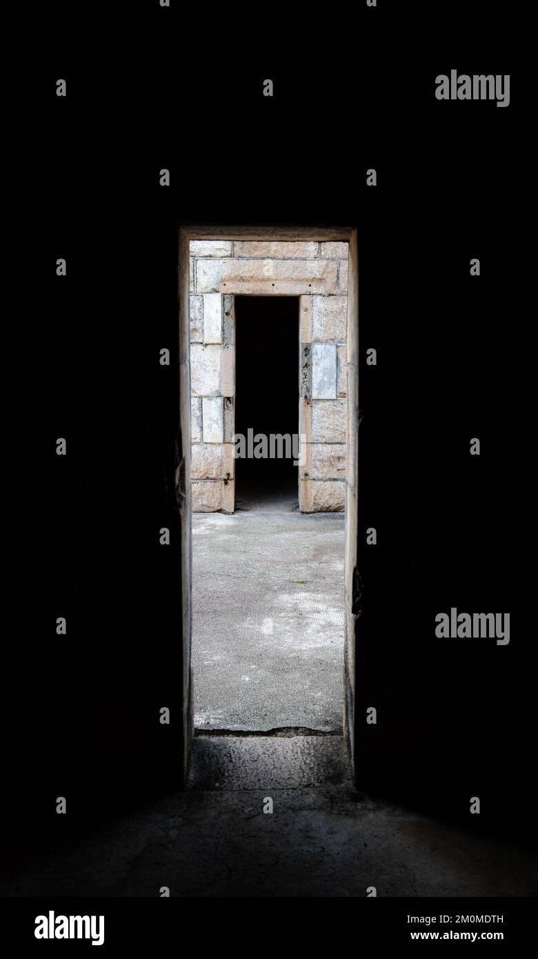 A vertical shot of the abandoned prison cells through the dark room ...