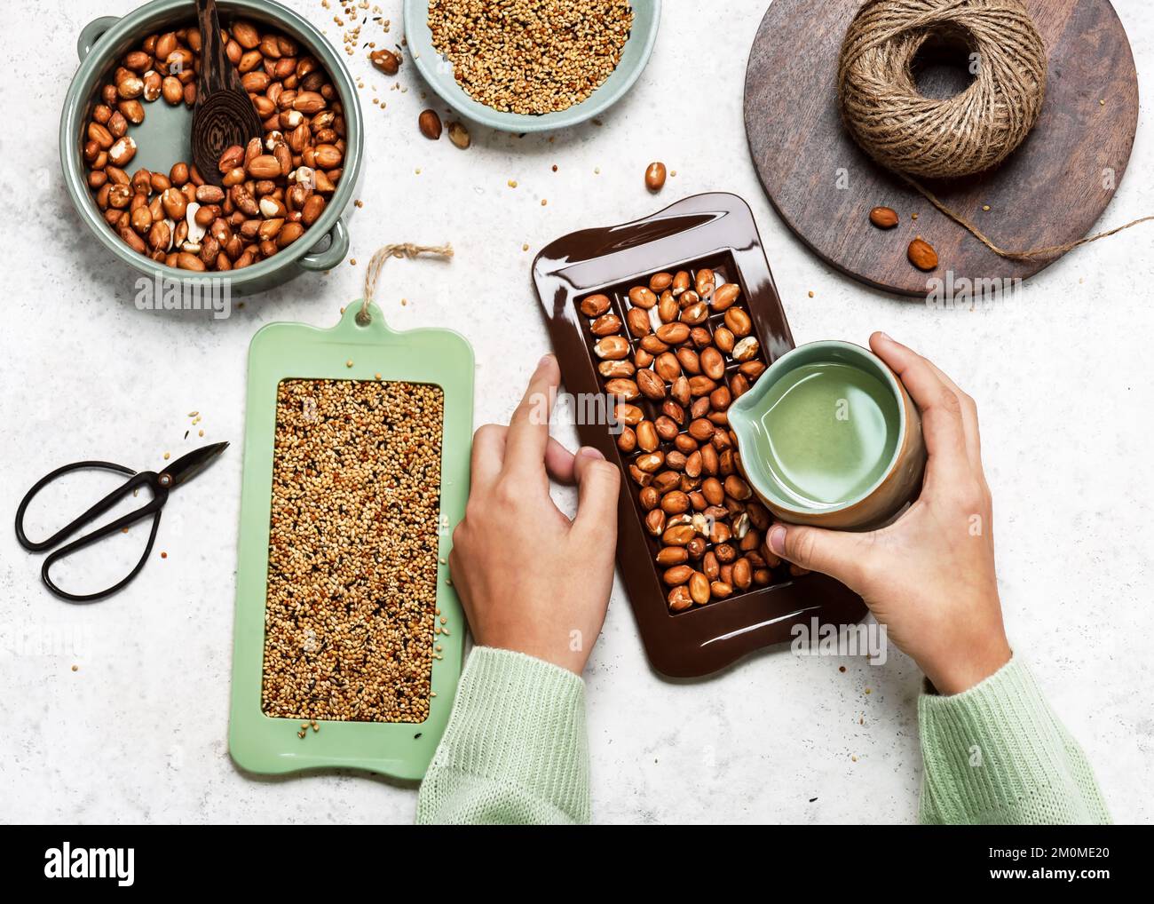 Step 2. Child pouring melted coconut fat into the form with birdseeds ...