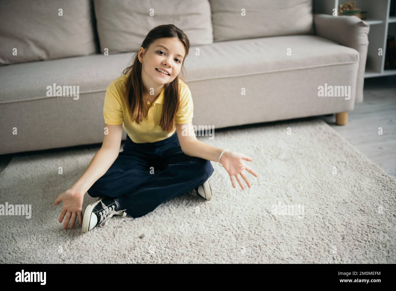 high angle view of cheerful girl sitting on floor with crossed legs and ...