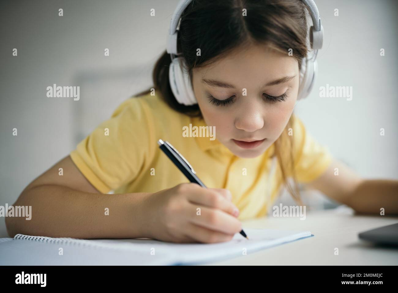 focused girl in headphones writing with pen during homeschooling Stock ...