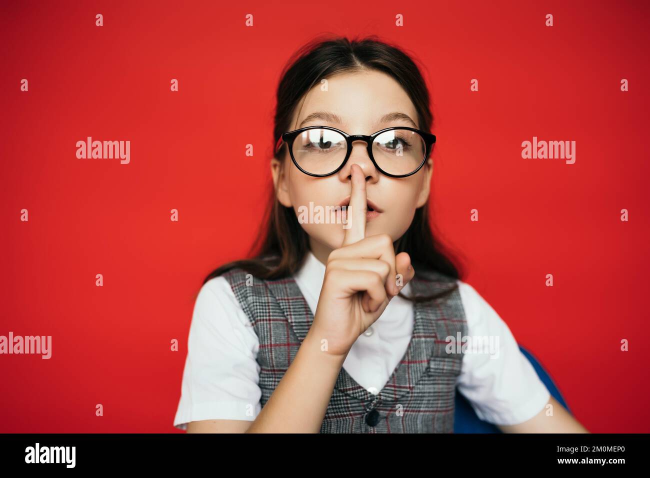 portrait of preteen girl in eyeglasses looking at camera and showing ...